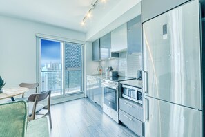 Uma cozinha moderna com eletrodomésticos de aço inoxidável, uma área de refeições com vista e uma varanda com vista para a cidade.