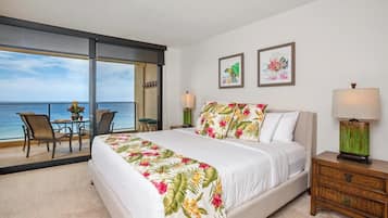 Quarto de hotel com cama, varanda com mesa e cadeiras e duas quadros na parede.