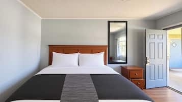 Quarto de hotel com cama, mesa de cabeceira, espelho e porta.