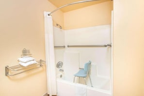 Chuveiro com porta de vidro, porta-toalhas e uma cadeira.