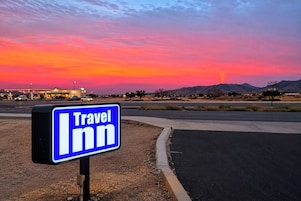 Placa de Travel Inn à frente de uma estrada, com o pôr do sol ao fundo.