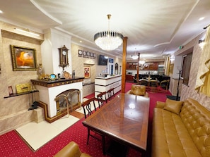 Uma área de recepção de hotel com balcão, assentos, lareira e um candelabro.