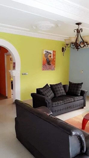 Uma sala de estar com sofá, mesa de centro e uma pintura na parede.