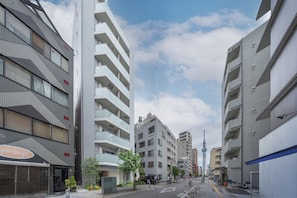 Uma rua urbana moderna com edifícios altos, céu claro e uma passarela para pedestres.
