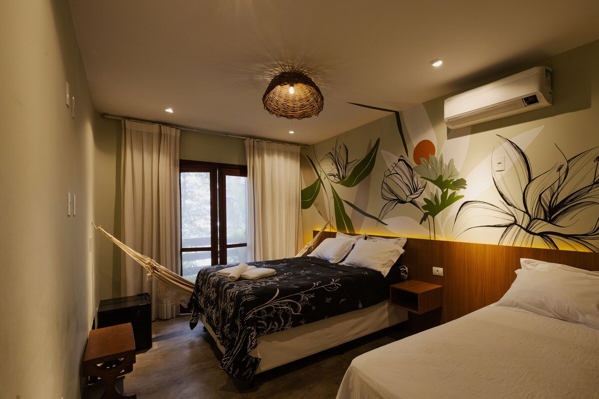 Quarto com cama, mesa de cabeceira, luminária pendente e ar-condicionado na parede.
