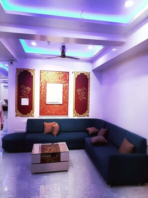 Uma sala de estar moderna com um sofá azul escuro, uma mesa de centro e painéis decorativos na parede.