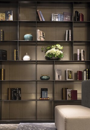Uma estante com diversos livros, objetos decorativos e um vaso com flores.