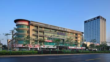 Um hotel com vários andares, com uma placa de destaque 'Paco Hotel', um '1618 Pub' no andar térreo e um edifício alto adjacente.