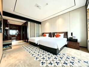Quarto de hotel moderno com cama grande, mesa de cabeceira e tapete estampado.