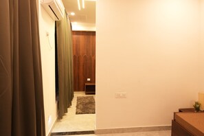 Um corredor com uma porta de madeira, um tapete pequeno e uma tomada na parede.