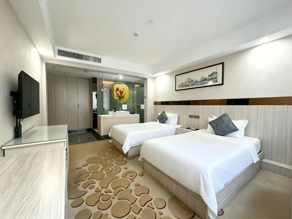 Quarto de hotel com duas camas, televisão, banheiro e vista para a cidade.