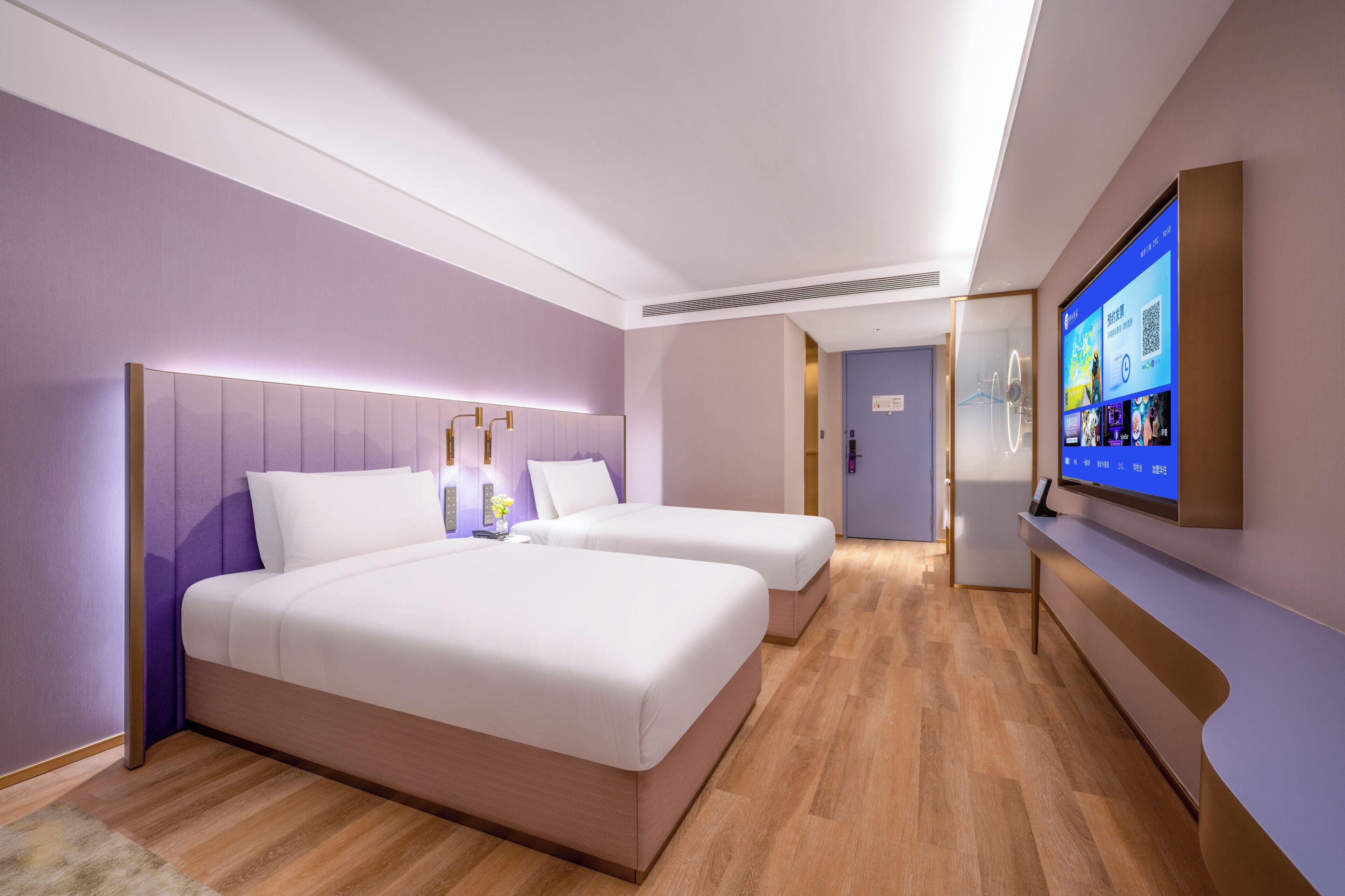 Quarto de hotel moderno com duas camas, TV de tela plana e piso de madeira.