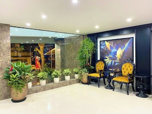 Um hall com área de estar, plantas em vasos e uma janela grande.