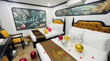 Quarto de hotel com duas camas, um mural com folhagem tropical e um minibar.