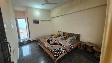 Quarto com cama, ventoinha no teto, porta e pequena janela.