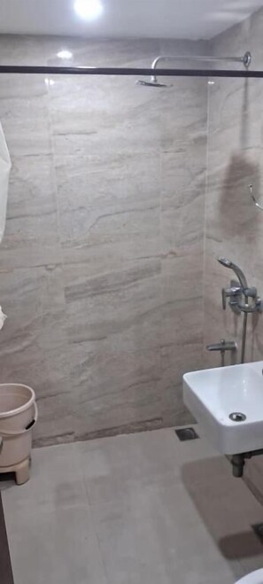 Casa de banho com cabine de chuveiro em vidro, lavatório e sanita.
