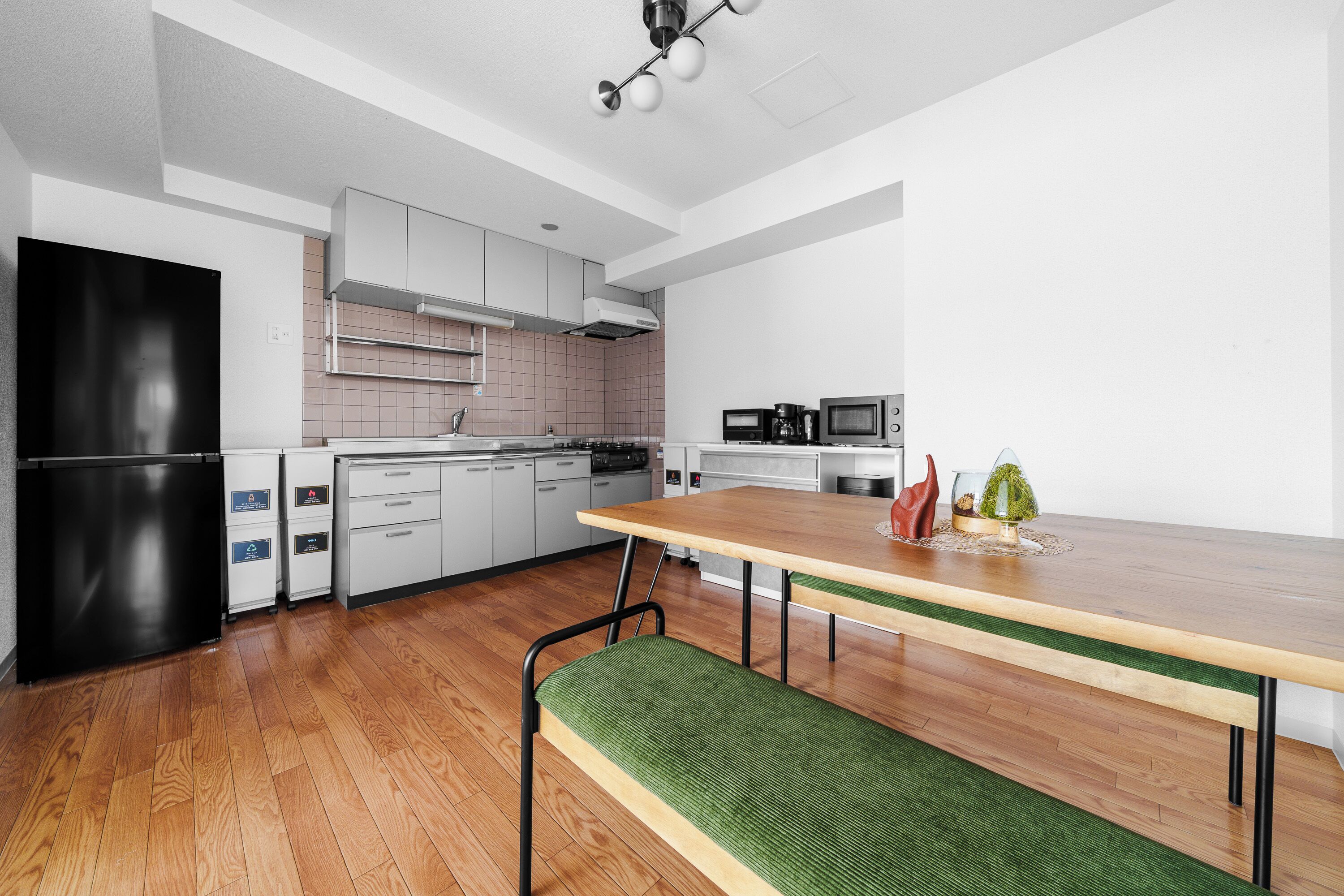 Cozinha moderna com eletrodomésticos de aço inoxidável, uma mesa de jantar de madeira e um banco.