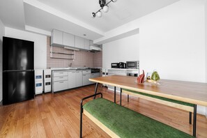 Cozinha moderna com eletrodomésticos de aço inoxidável, uma mesa de jantar de madeira e um banco.