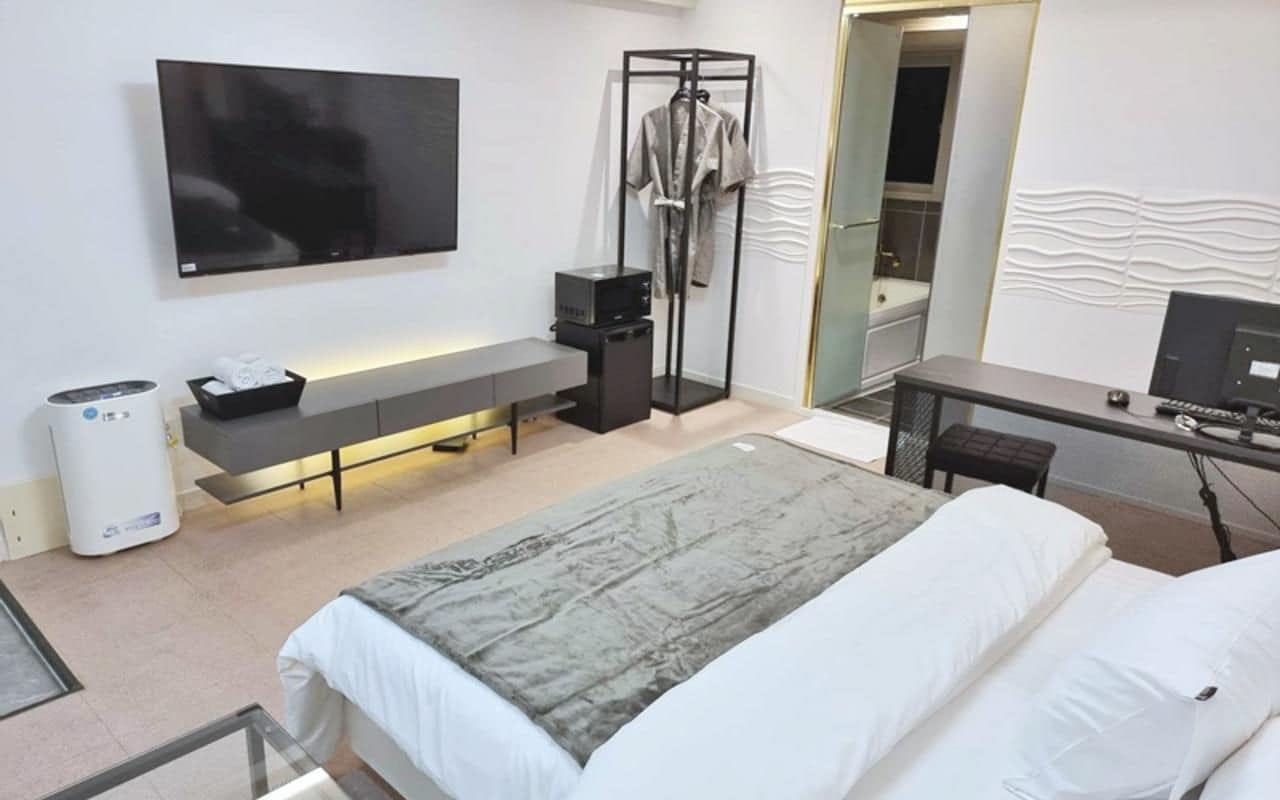 Quarto de hotel moderno com cama, televisão de tela plana, escrivaninha e closet espaçoso.