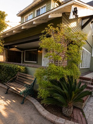 Uma casa com varanda, um banco e uma árvore.
