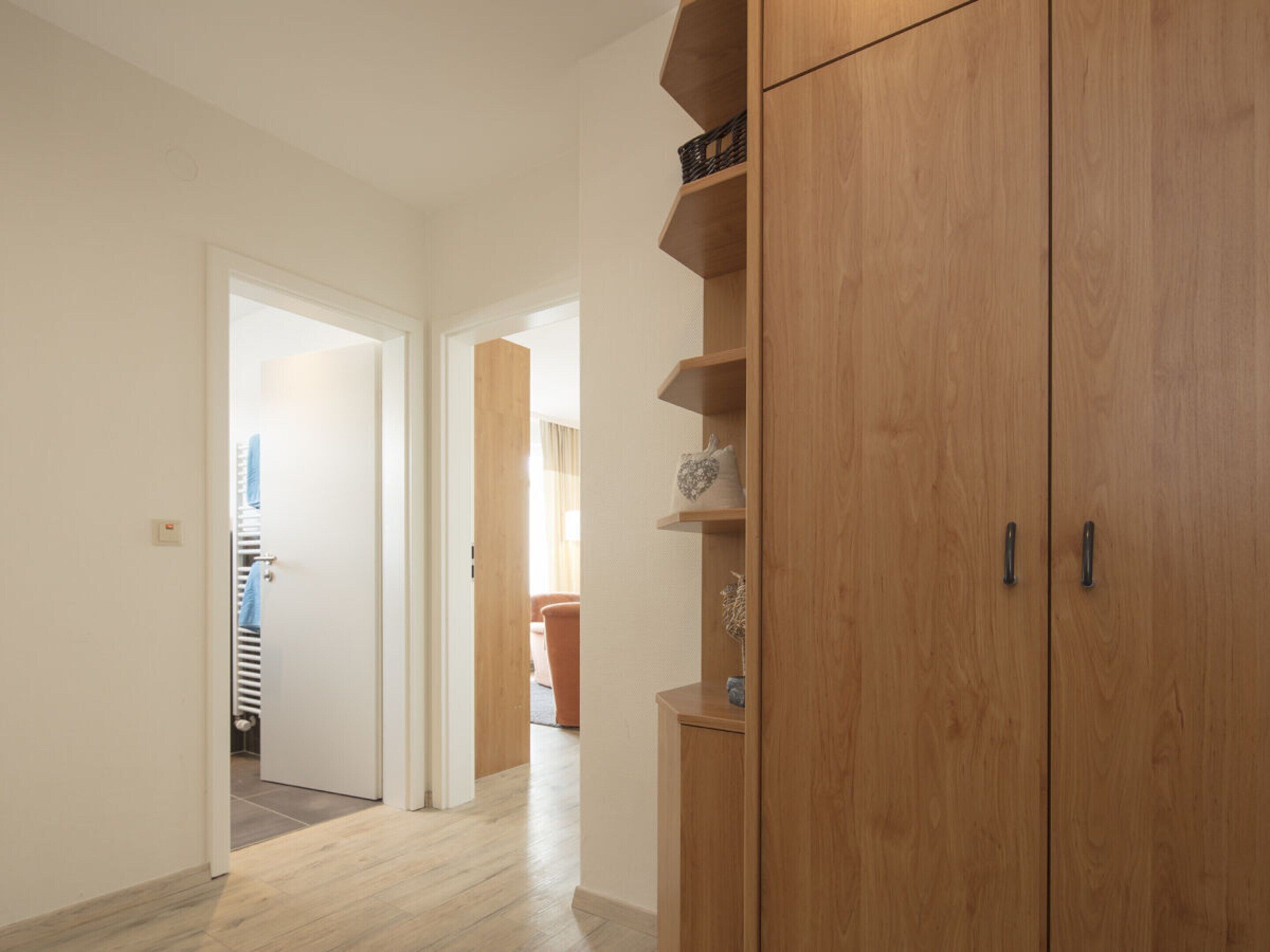 Corredor com armários de madeira e uma porta que dá para outro quarto.