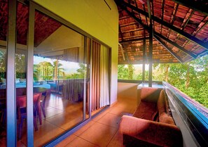 Varanda com porta de vidro que dá para uma área de refeições, espaço de estar acolchoado e vista para o verde.
