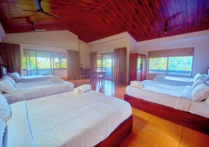 Quarto de hotel com duas camas, uma mesa de jantar e vista para o exterior.