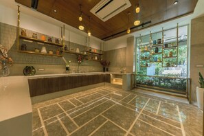 Cozinha moderna com piso de mármore, teto de madeira e iluminação pendente.