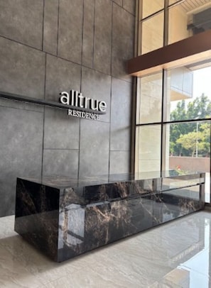 Uma receção com balcão de mármore e placa com a inscrição 'alltrue RESIDENCE'.