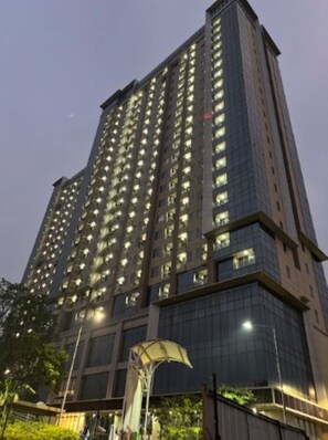 Um edifício alto com vários andares, janelas amplas e fachada bem iluminada.