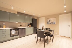 Cozinha moderna com armários cinza, mesa de jantar com cadeiras e um quadro na parede.
