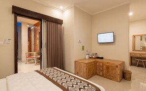 Quarto de hotel com uma cama, escrivaninha de madeira, televisão e espelho.