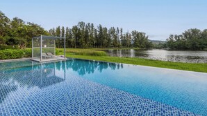 Piscina com vista desobstruída para um lago e árvores ao fundo.