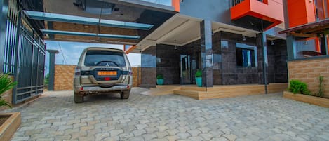 Um edifício de vários andares com rampa coberta e um SUV estacionado.