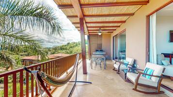 Uma varanda com rede, área de estar externa e vista para a paisagem.