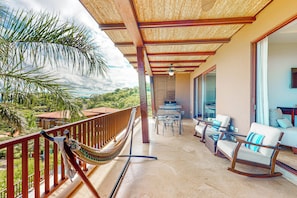 Uma varanda com rede, área de estar externa e vista para a paisagem.