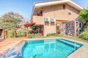Imóvel residencial com piscina, varanda coberta e muro de pedra.