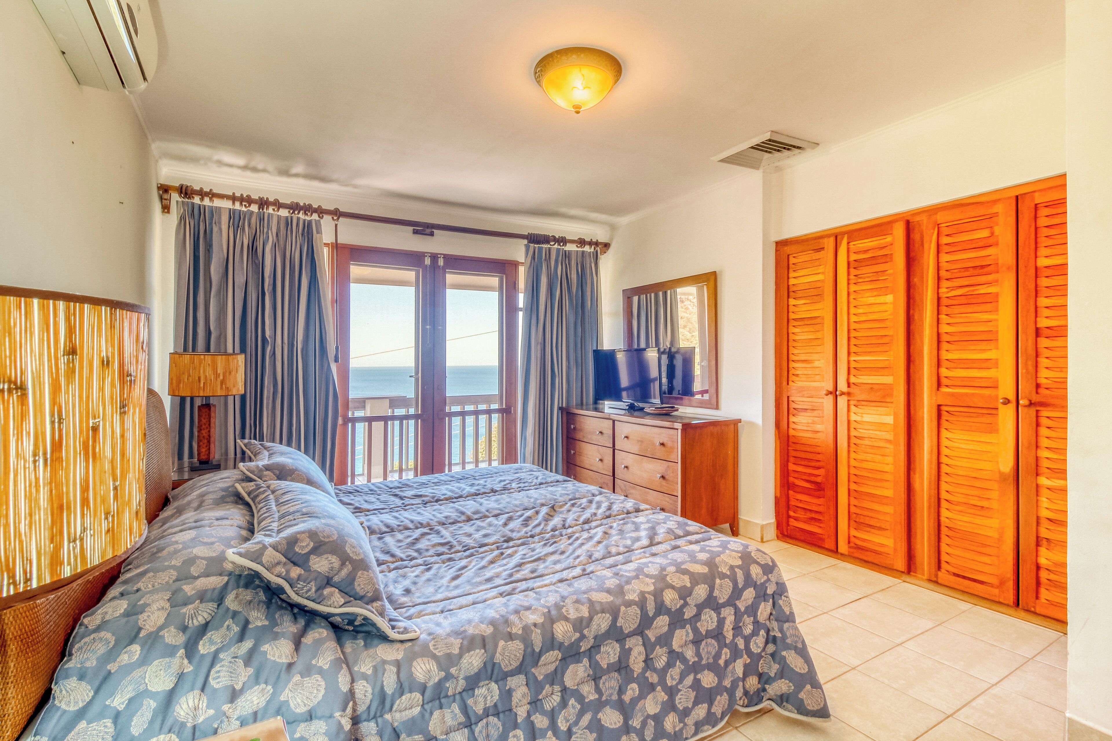 Quarto com cama, cortinas, televisão e armários de madeira.