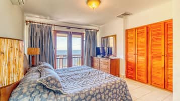 Quarto com cama, cortinas, televisão e armários de madeira.