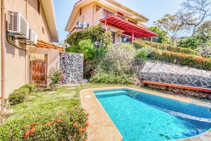 Piscina com parede de pedra e área com telhado vermelho.