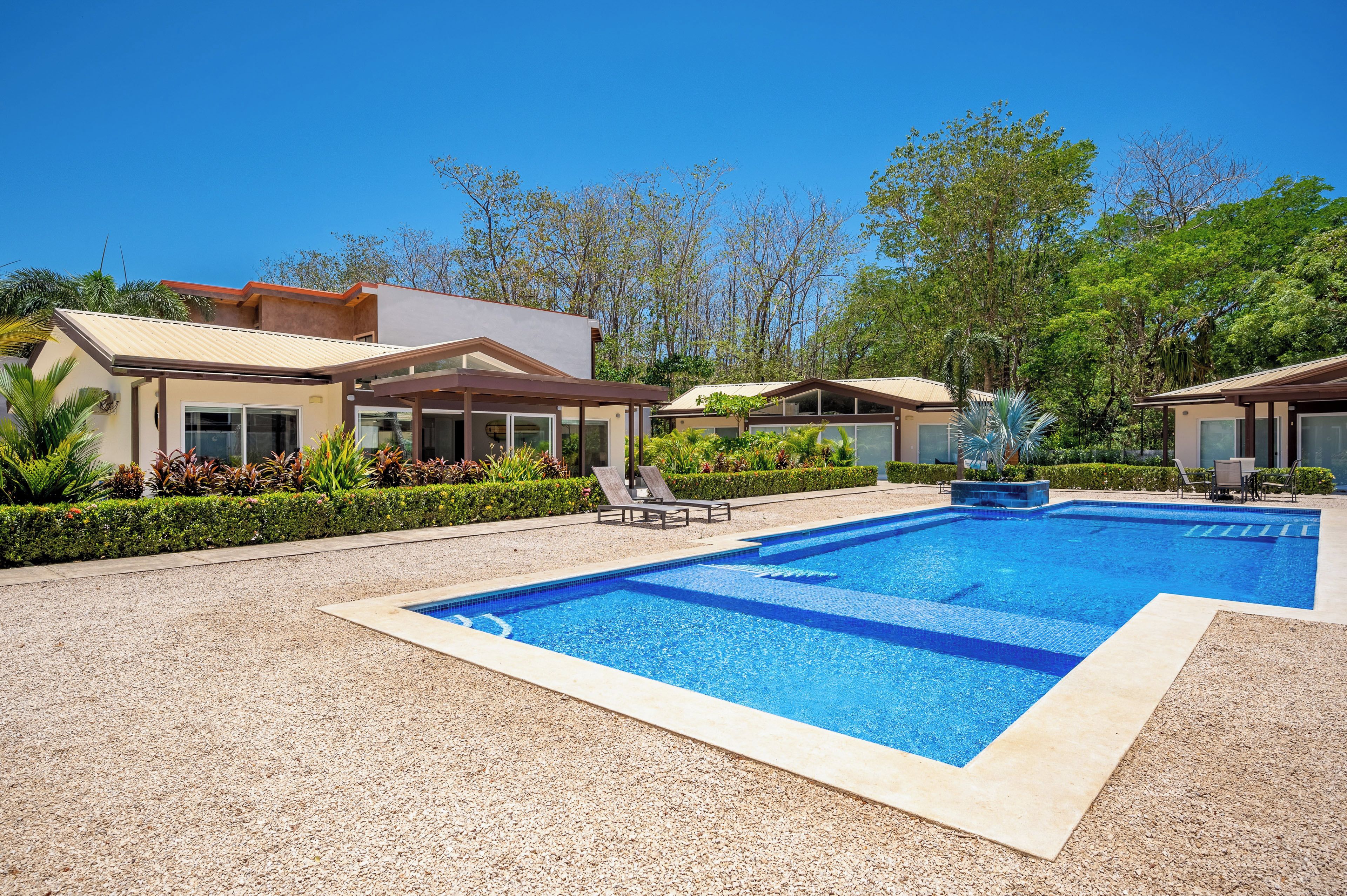 Um resort moderno com piscina, espreguiçadeiras e um jardim bem cuidado.