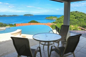 Área da piscina com vista para o mar e uma ilha ao longe.