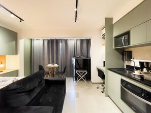 Cozinha moderna com micro-ondas, cafeteira e área de jantar com sofá e cadeiras.