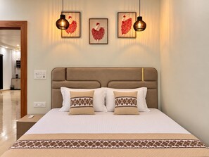 Quarto de hotel com cama, duas mesas de cabeceira, painel de cabeceira e arte na parede.
