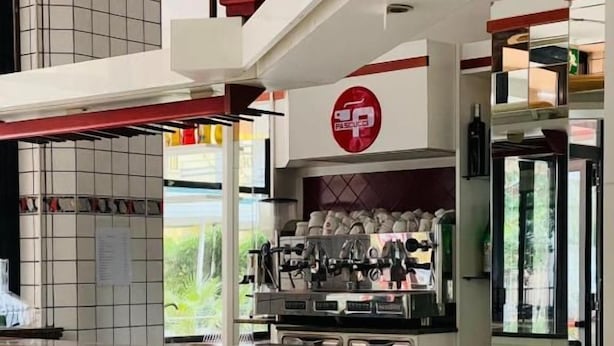 Cozinha moderna com área de bar, banquetas vermelhas e máquina de café.