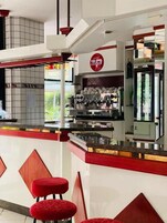 Cozinha moderna com área de bar, banquetas vermelhas e máquina de café.