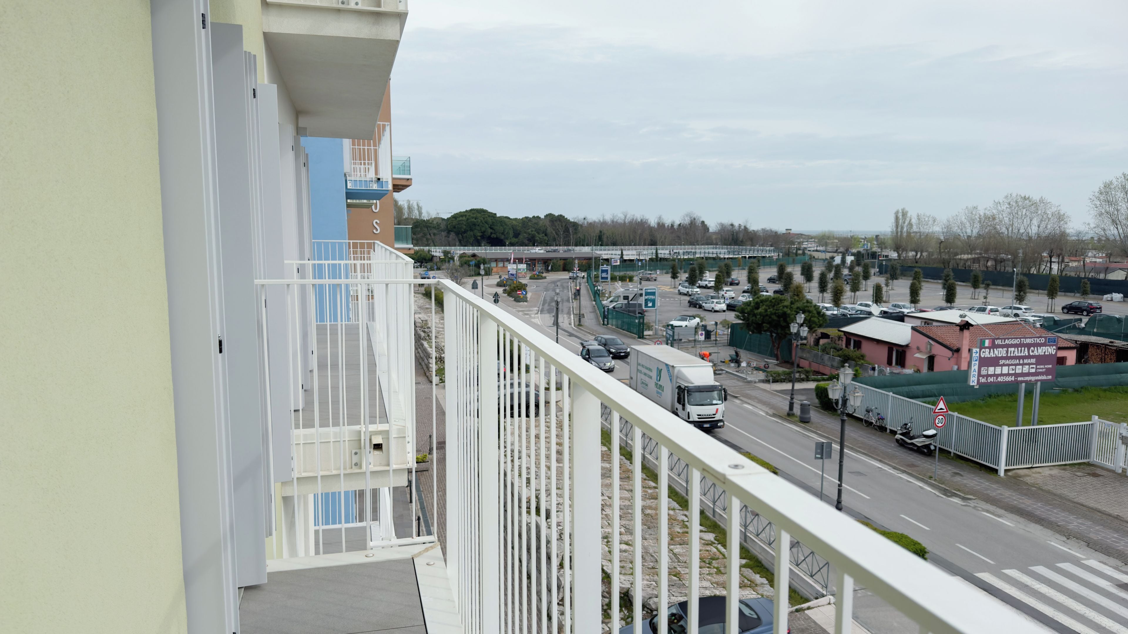Varanda com vista para uma estrada, área de estacionamento e um edifício com uma placa.