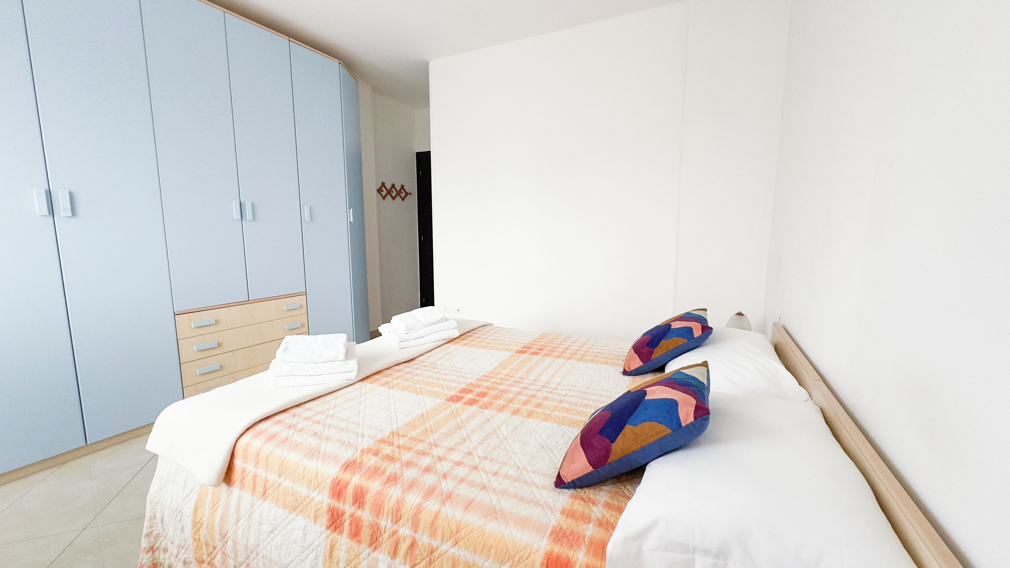 Quarto com cama, guarda-roupa e mesa de cabeceira.