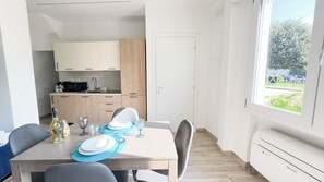 Cozinha moderna com armários de madeira, uma mesa de jantar posta para dois e vista para o exterior através de uma grande janela.