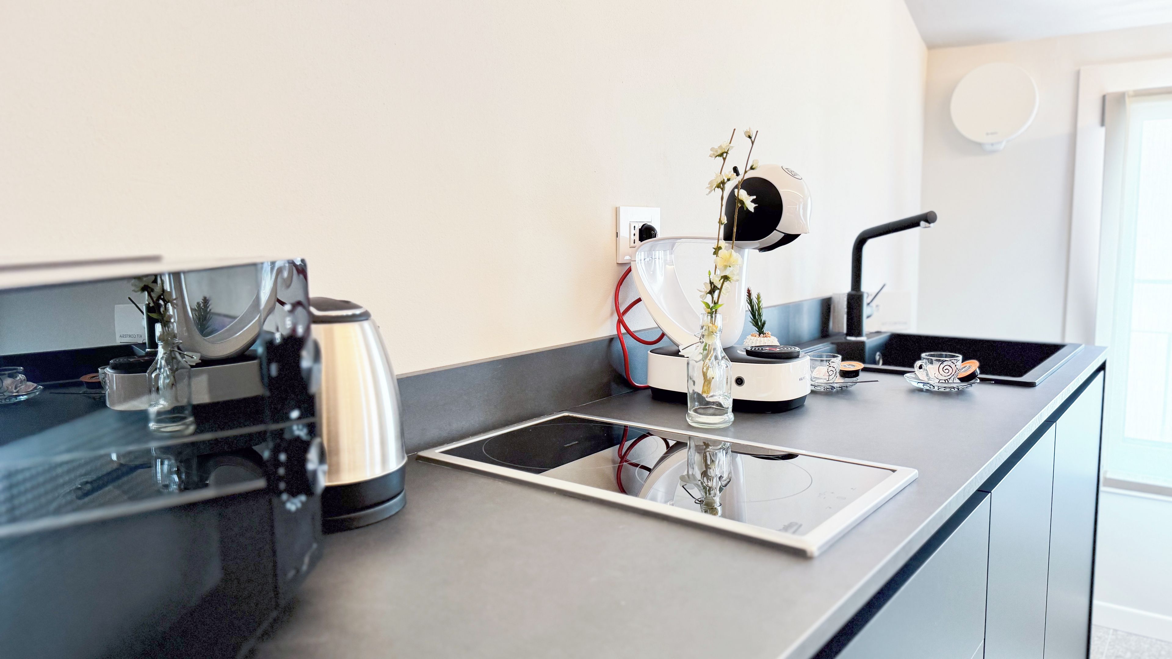 Cozinha moderna com fogão de indução embutido, máquina de café e um copo de água na bancada.